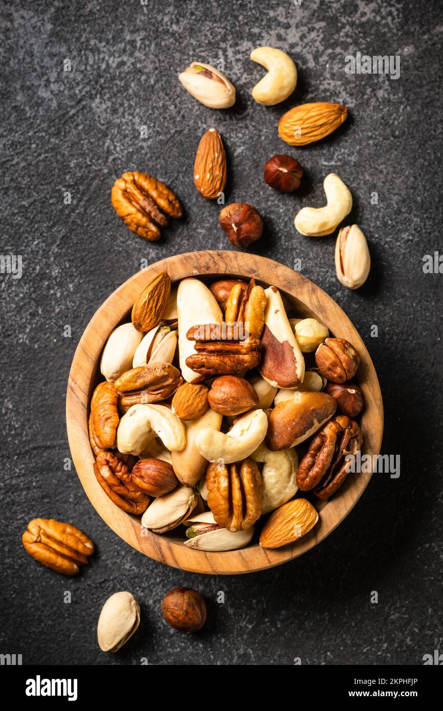 Assortment of nuts in wooden bowl on dark stone table. Cashew ...