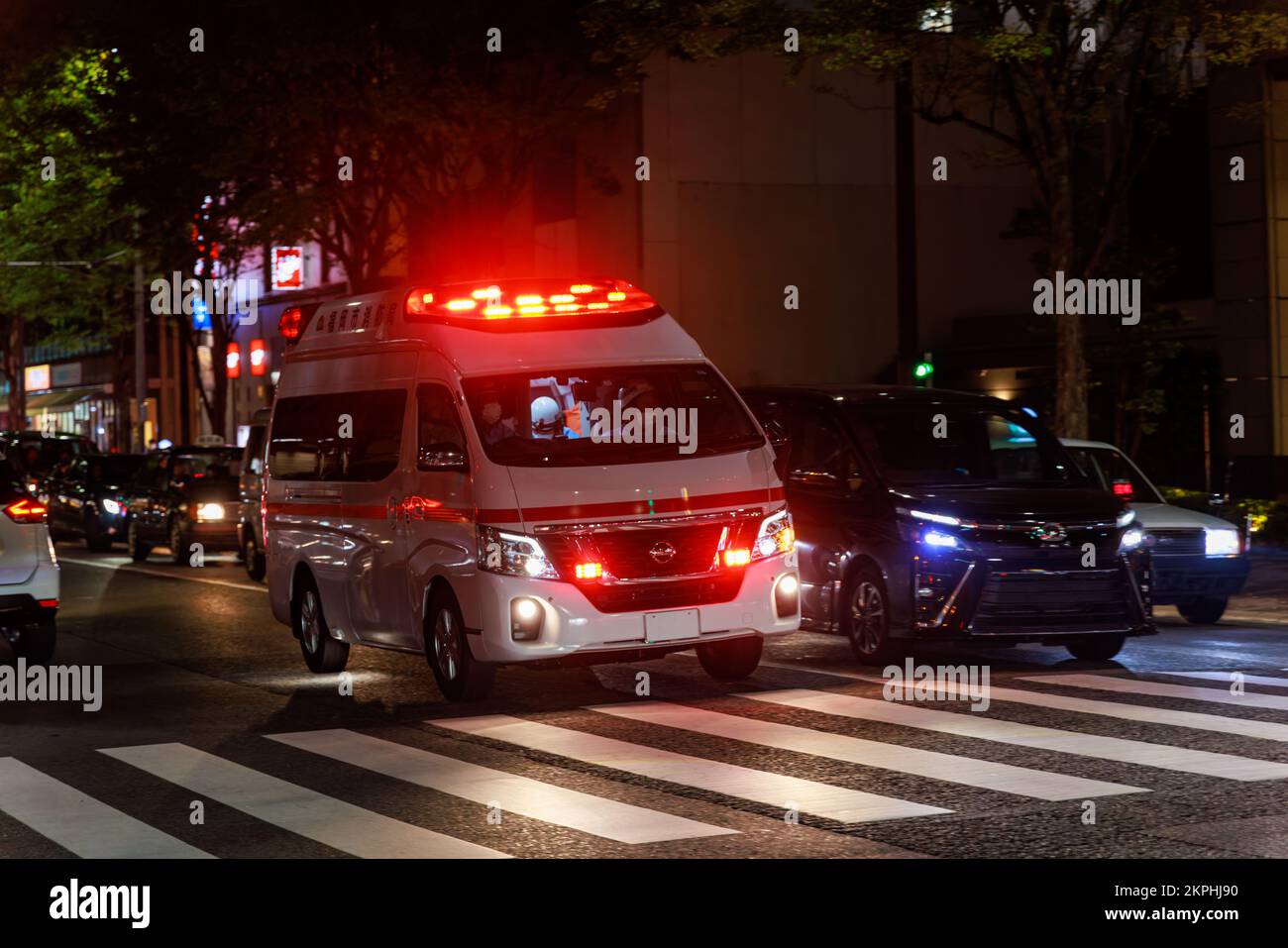 Ambulance with flashing red lights in heavy traffic at night Stock ...