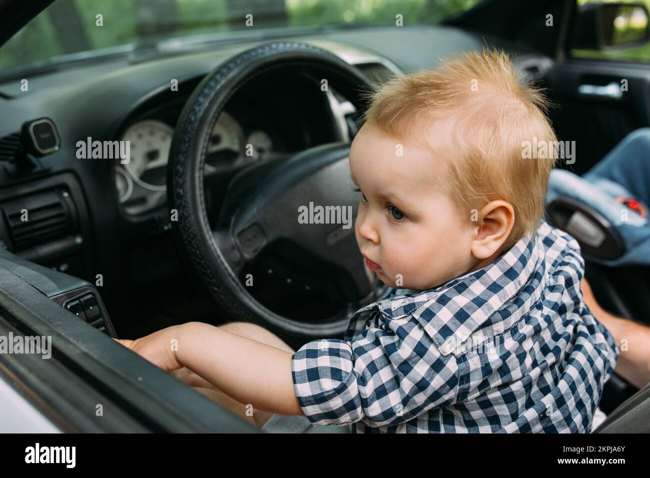 Dad shows his little son how to drive car while sitting behind wheel ...