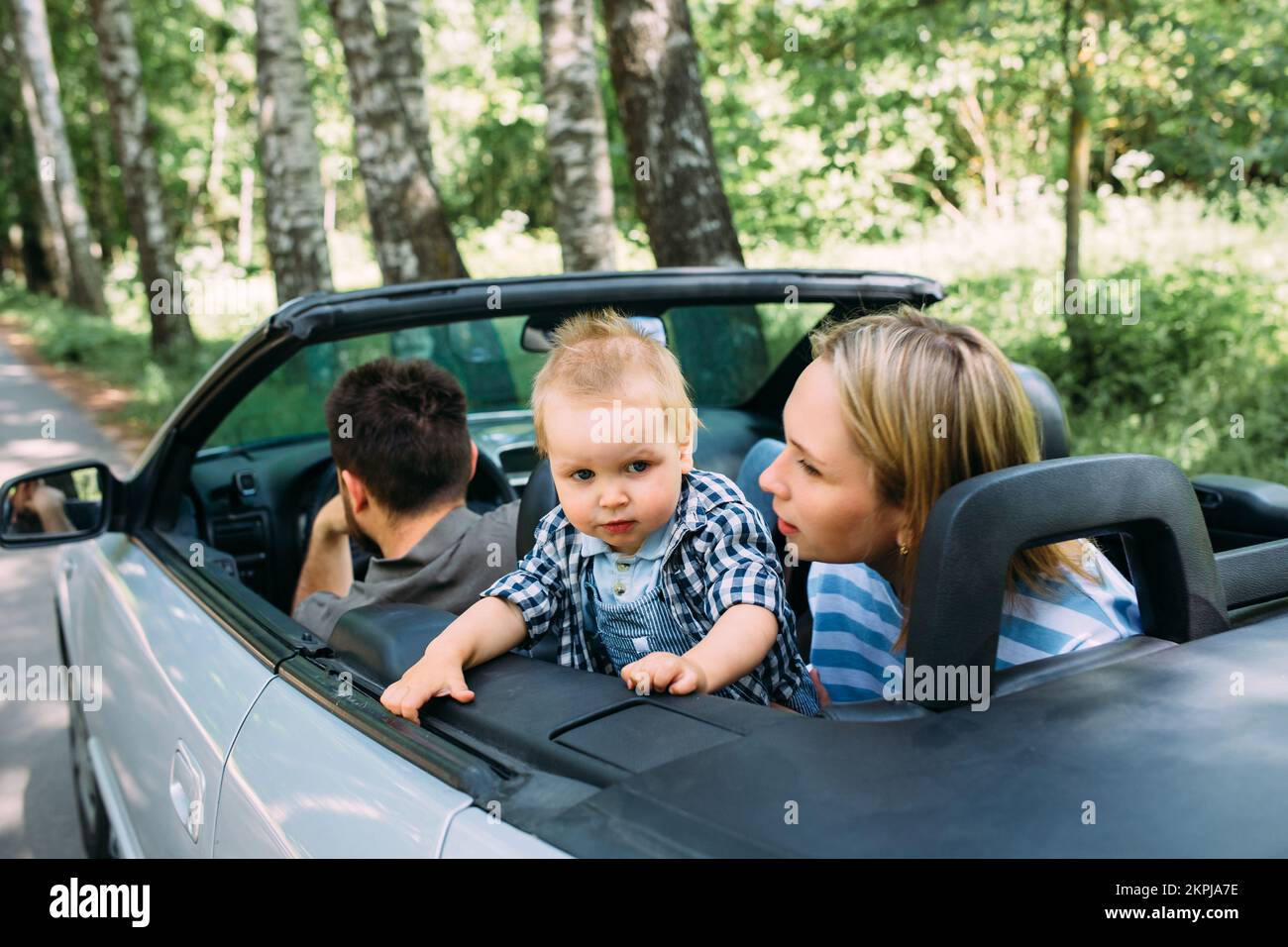 Mom, dad and little son in a convertible car. Summer family road trip ...