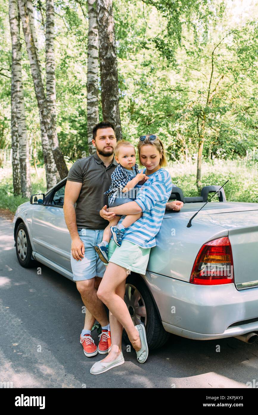 Mom, dad and little son in a convertible car. Summer family road trip ...