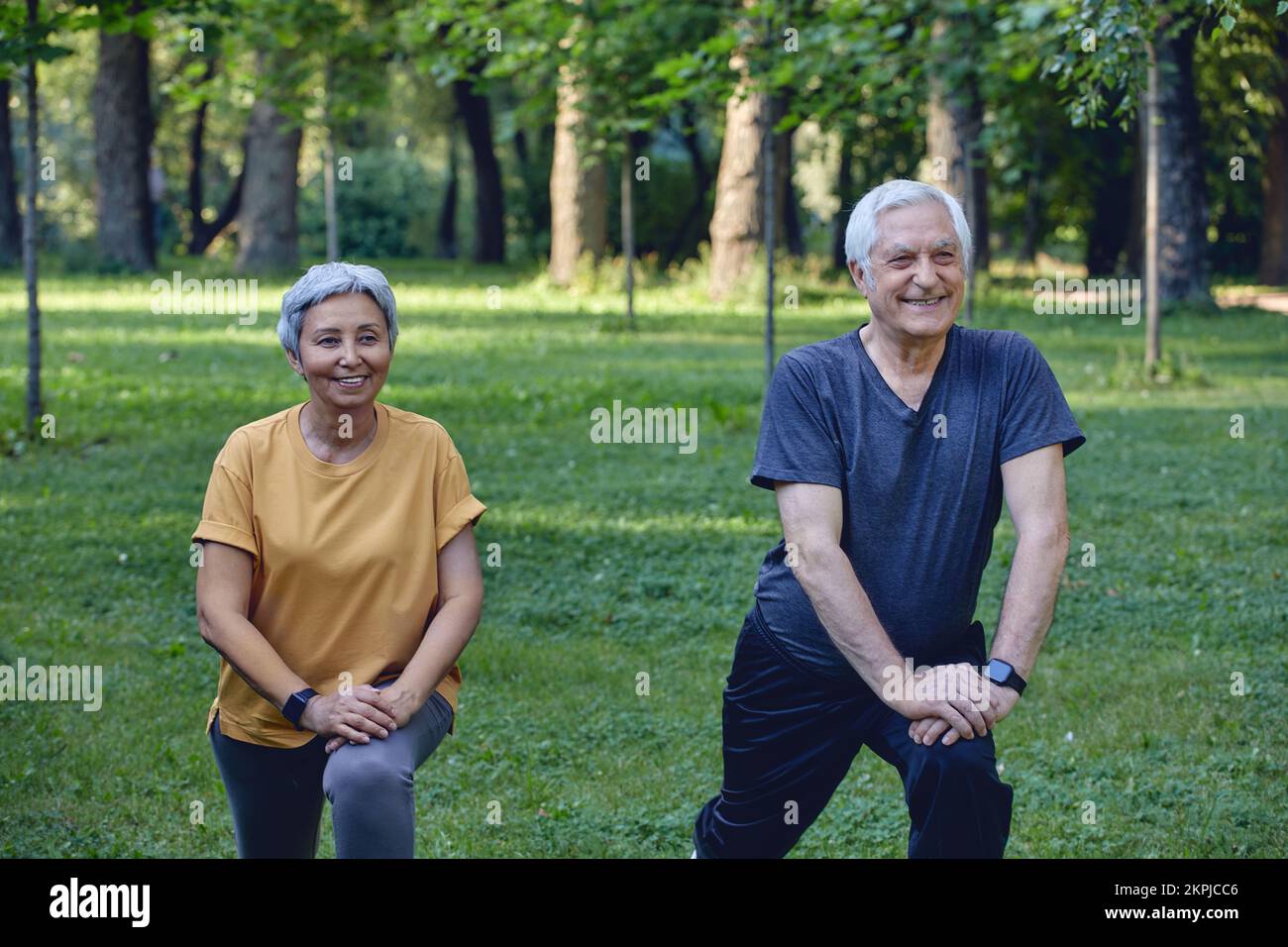 Senior spouses doing sportive exercises outdoor in summer park in the ...