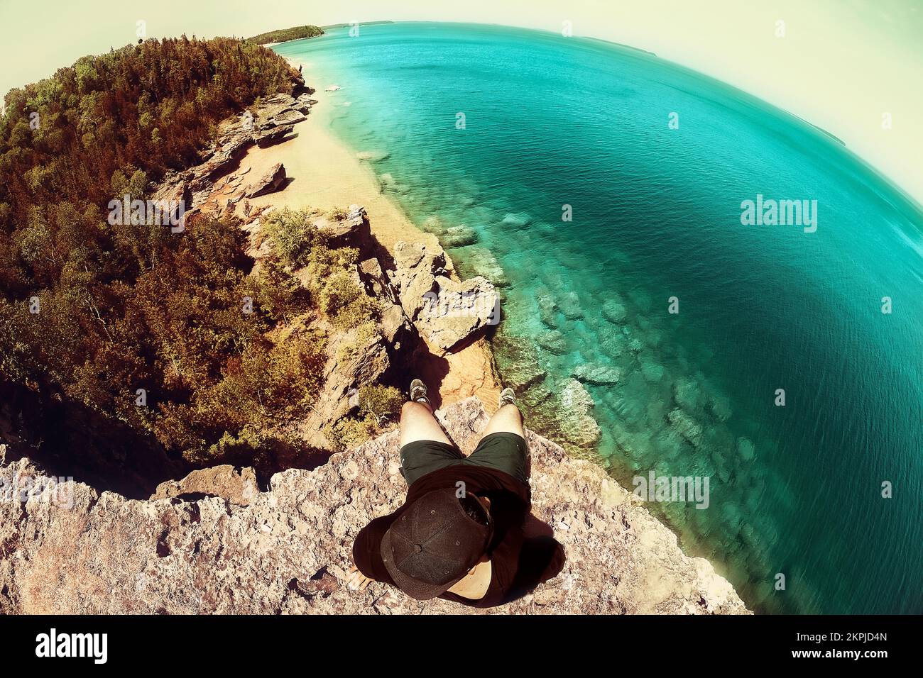 A man sitting on the edge of the abyss in a paradise beach Stock Photo ...