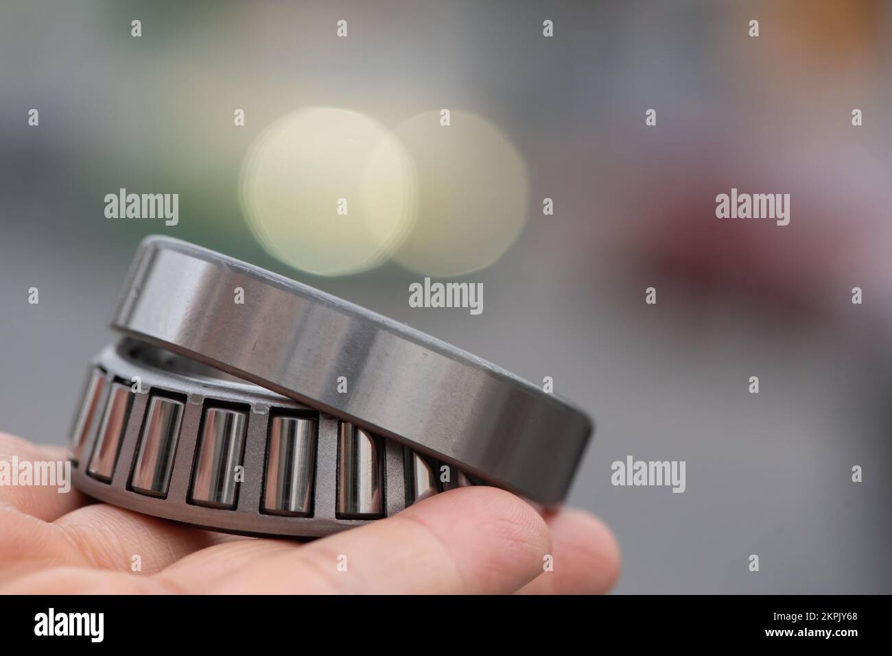 Hand holding Automotive wheel tapered roller bearing on road background ...