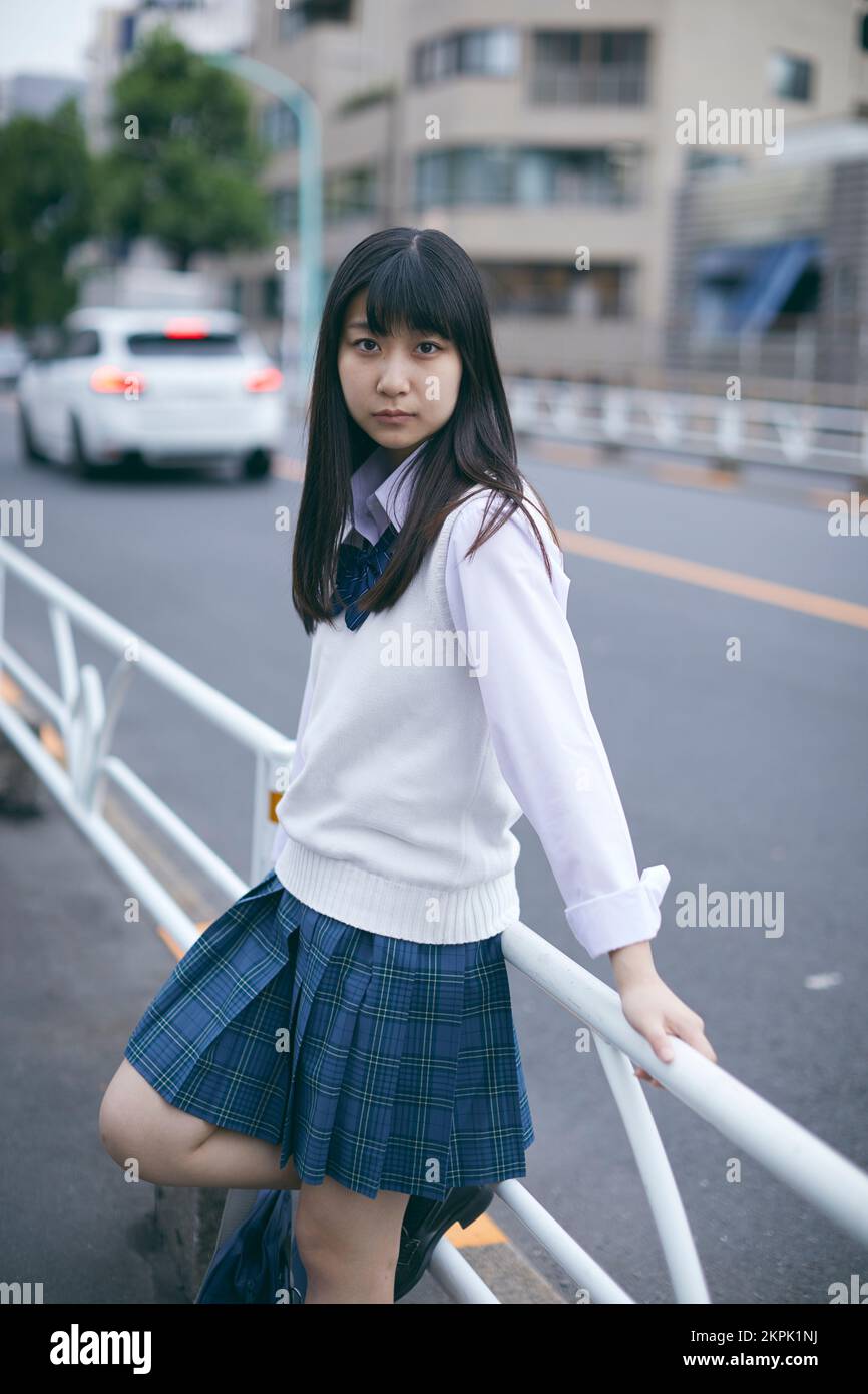 Japanese high school girl leaning against a guard pipe Stock Photo - Alamy