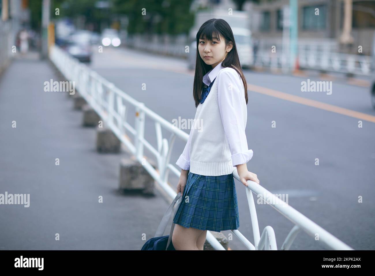 Japanese high school girl leaning against a guard pipe Stock Photo - Alamy