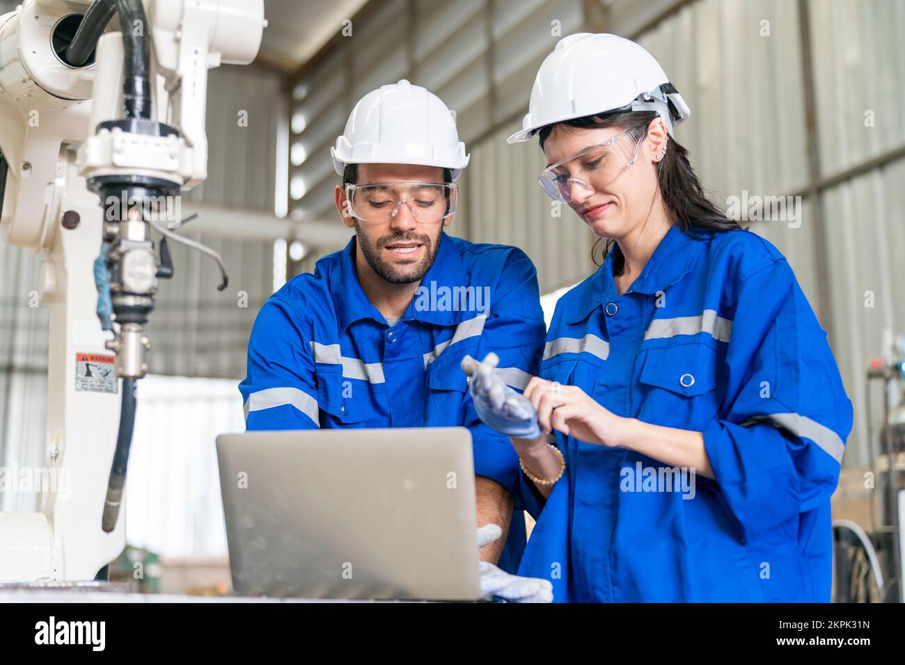 Robotics engineer working on maintenance of modern robotic arm in ...