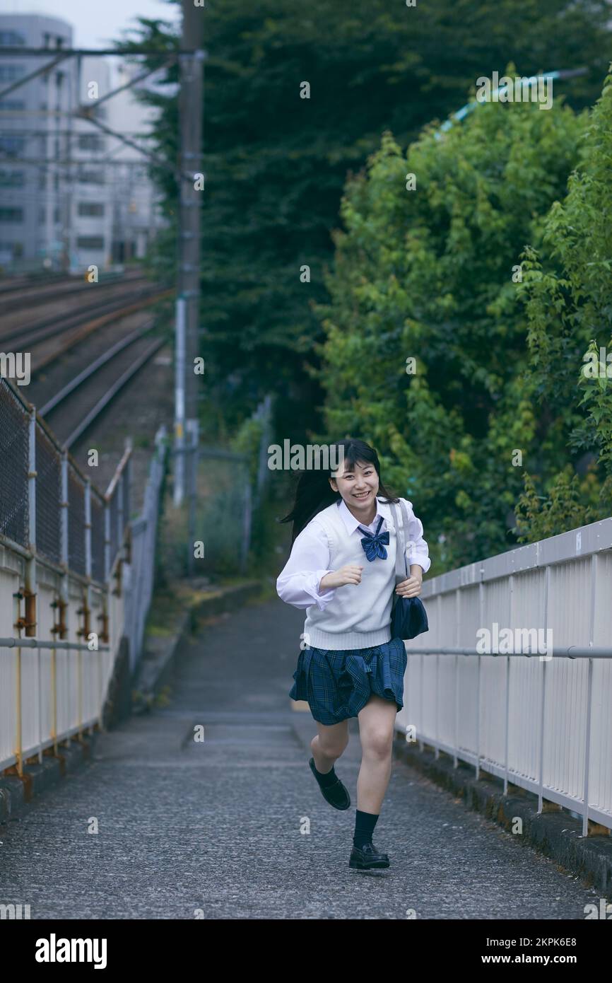 Japanese high school girl running on a pedestrian bridge Stock Photo ...