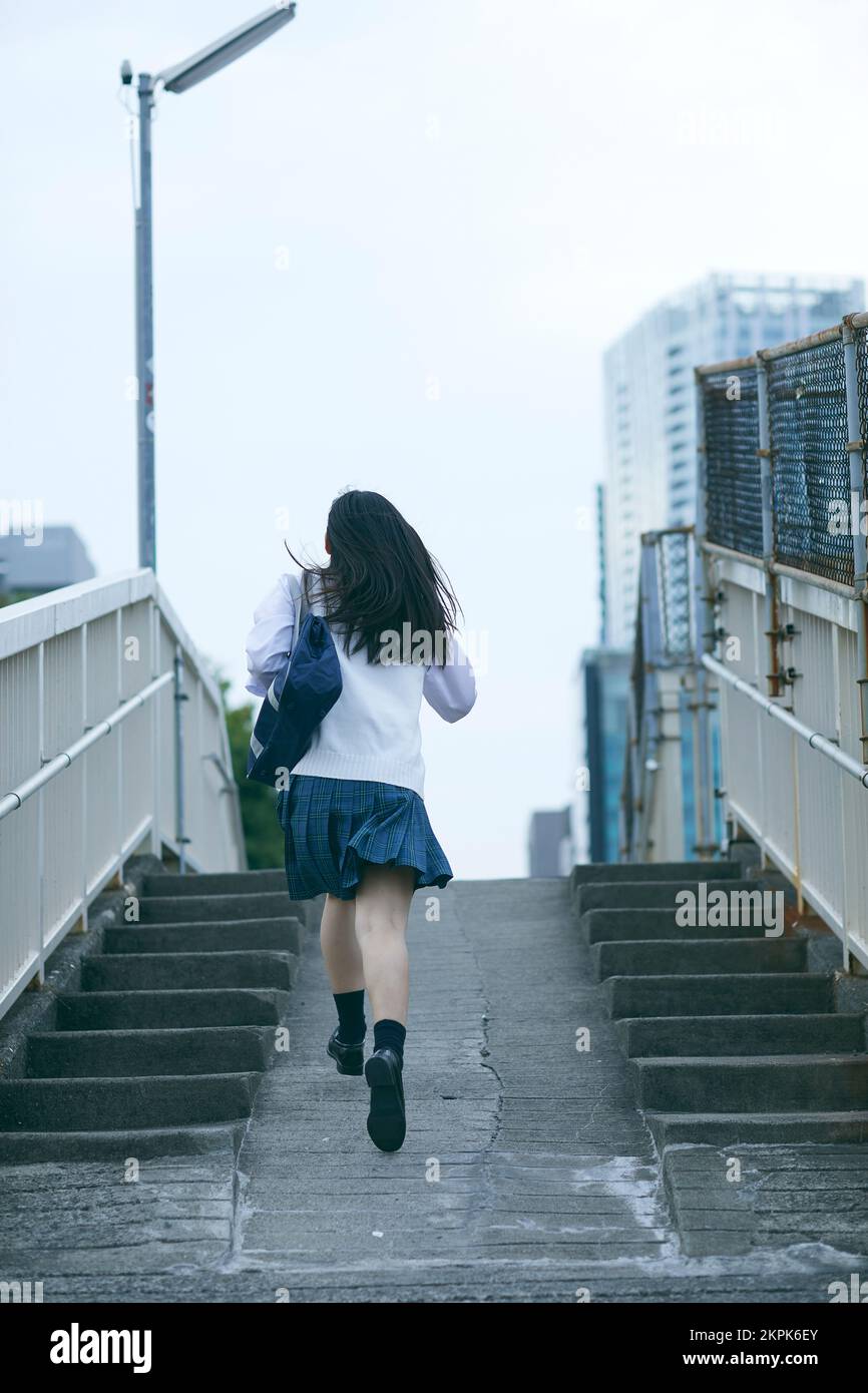 Japanese high school girl running on a pedestrian bridge Stock Photo ...