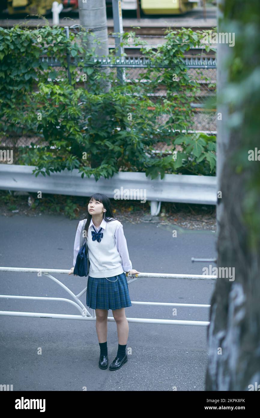 Japanese high school girl leaning against a guard pipe Stock Photo - Alamy