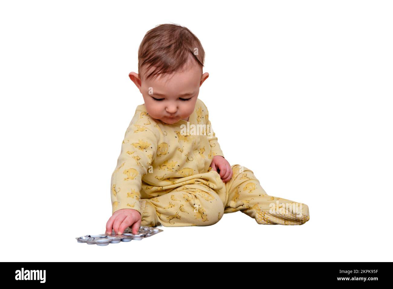 Toddler baby boy plays with medicines in a package while sitting on the ...