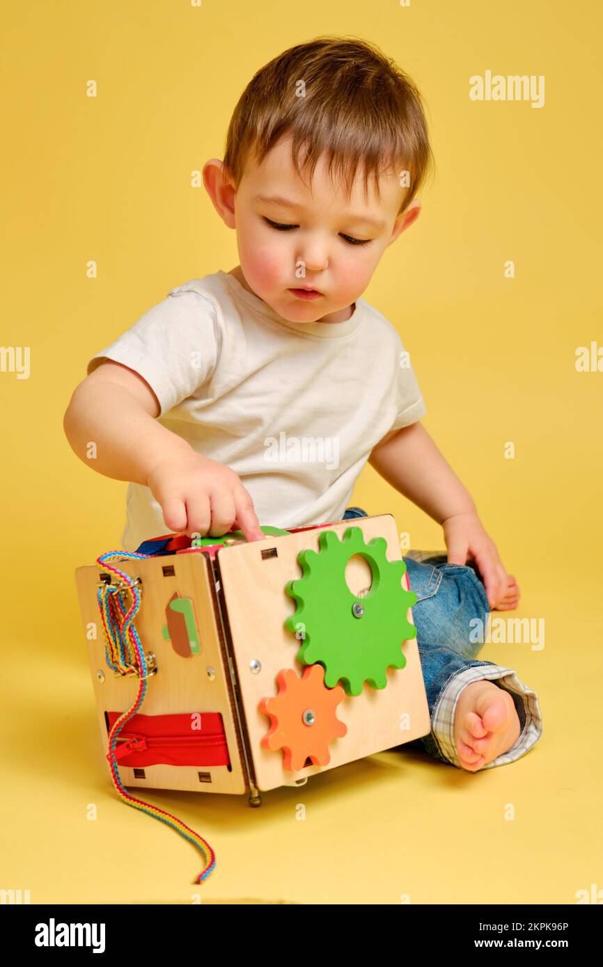 Toddler baby is playing logic educational games busyboard on a studio ...