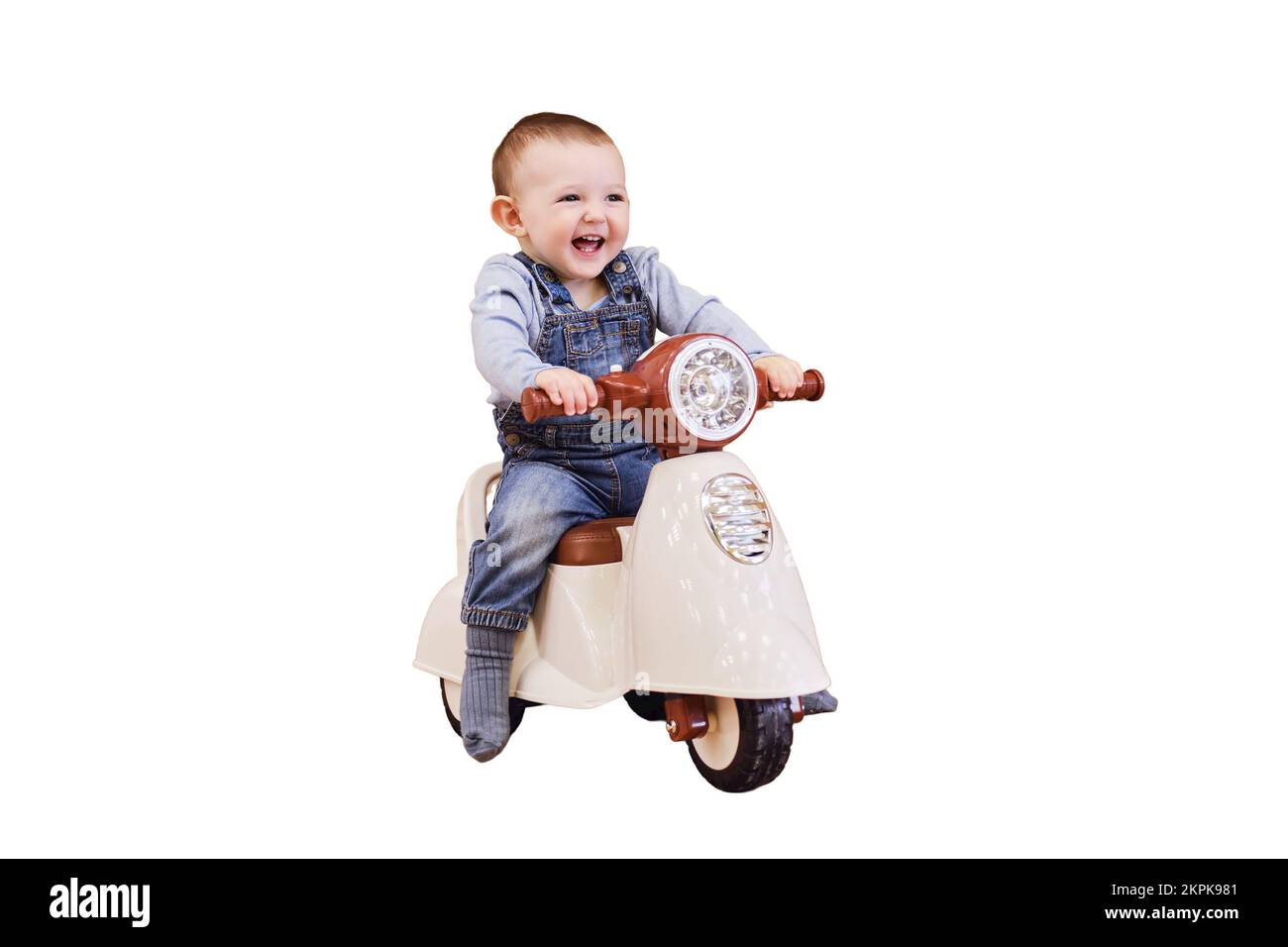 Happy baby boy rides a plastic children motorcycle in the playroom ...