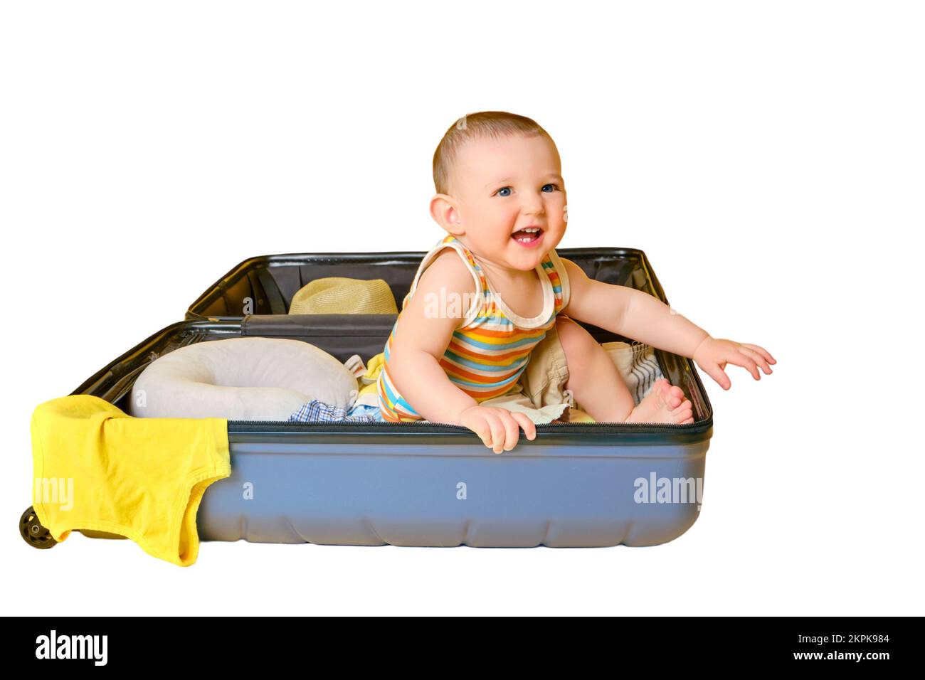 Baby toddler boy sits inside a suitcase with clothes, studio isolated ...