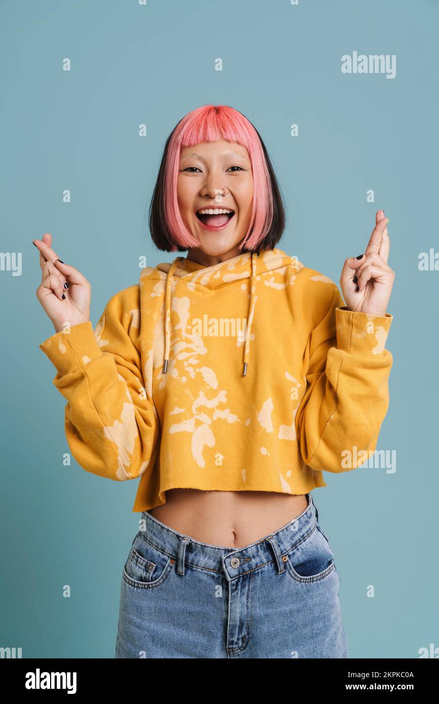 Asian girl with pink hair laughing while holding fingers crossed ...