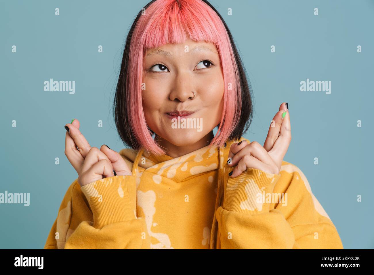 Asian girl with pink hair holding fingers crossed for good luck ...
