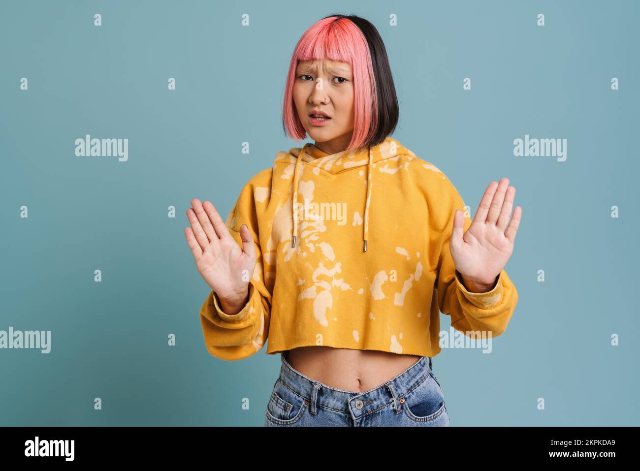 Asian girl with pink hair and piercing showing stop gesture at camera ...