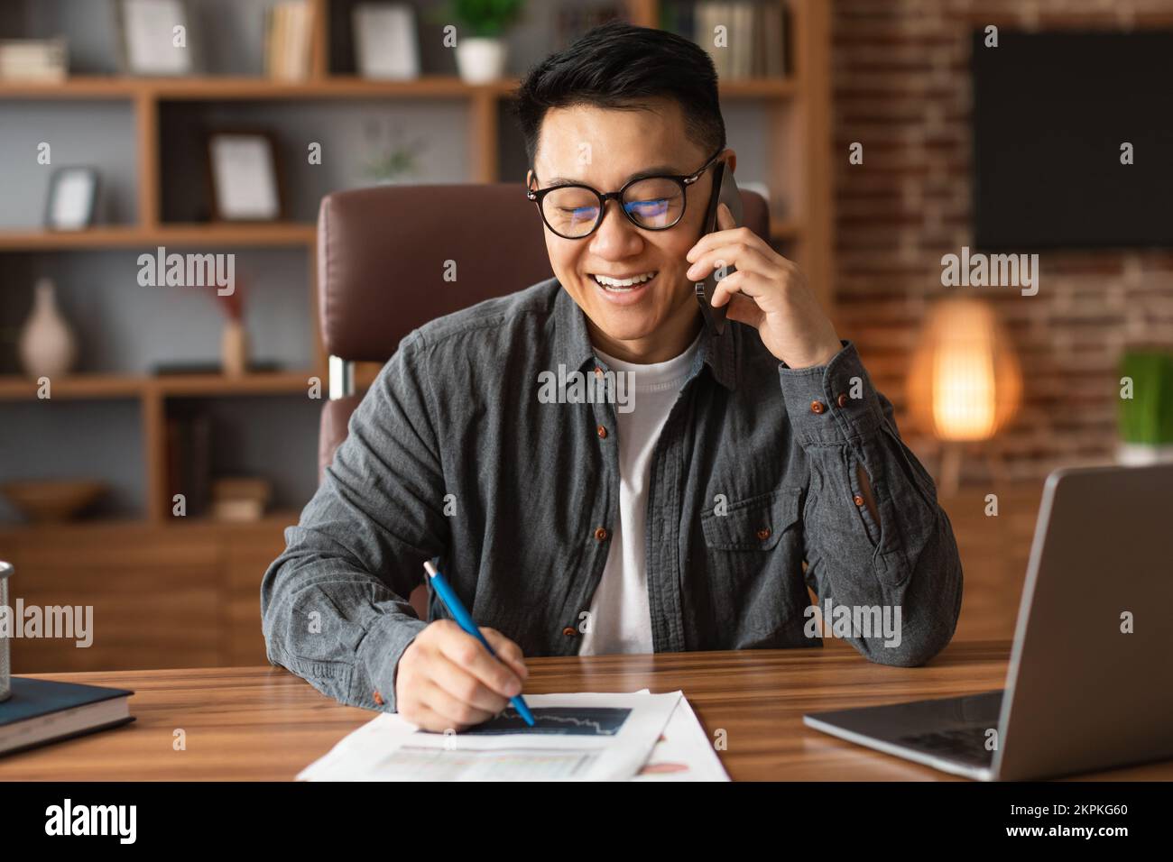 Happy busy adult asian man in glasses works with documents at table ...