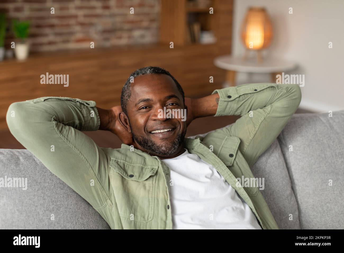 Cheerful middle aged african american man resting on sofa, enjoying ...
