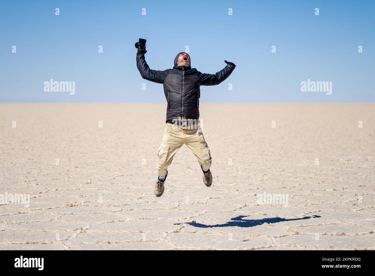 Happy man holding a camera jumping on the Salar de Uyuni (Uyuni Salt ...