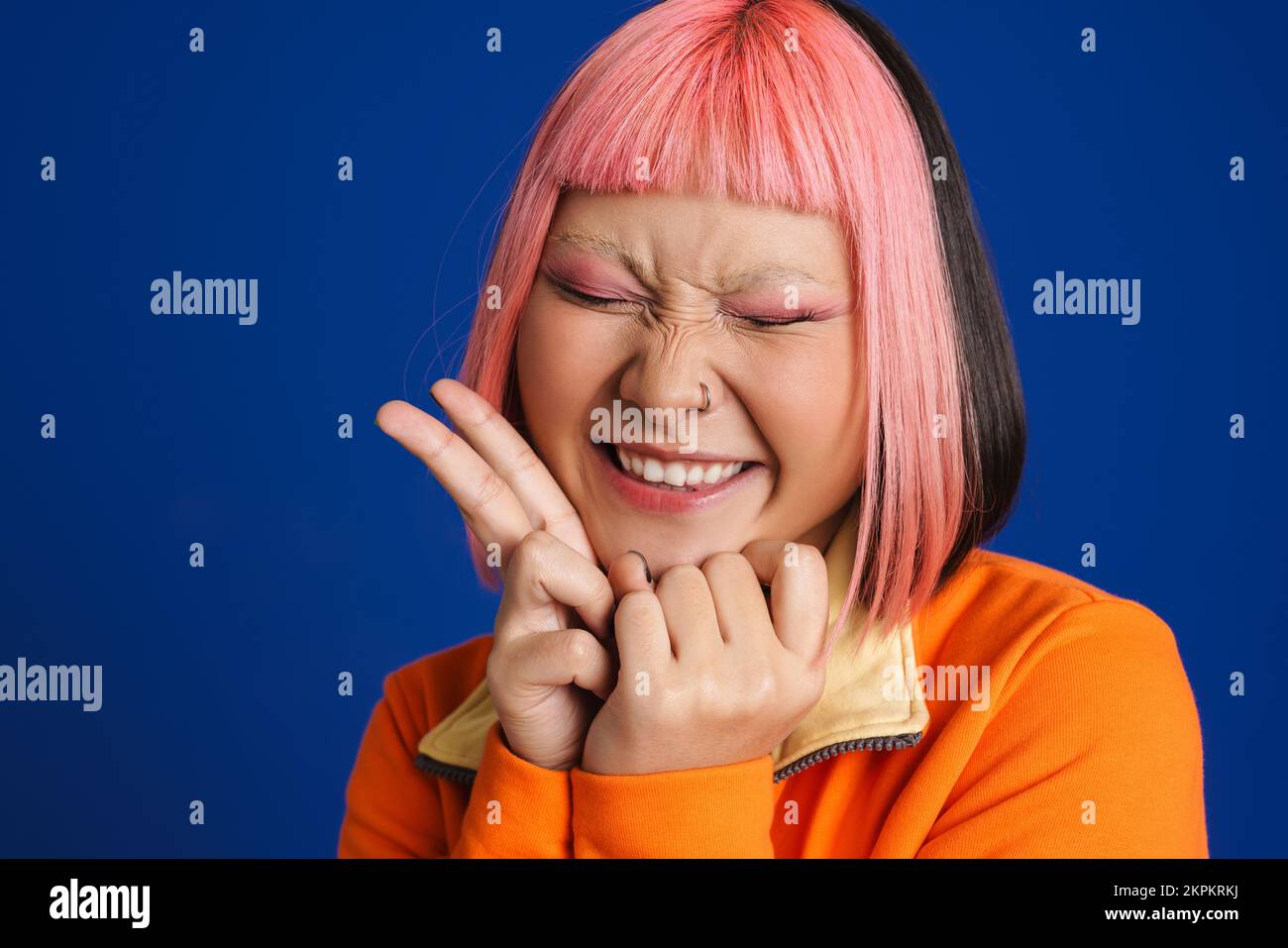 Asian girl with pink hair laughing while showing peace gesture isolated ...