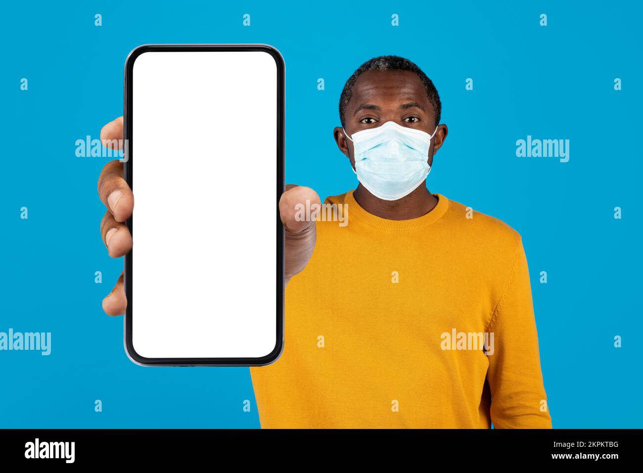 Black man in face mask showing smartphone with empty screen Stock Photo ...