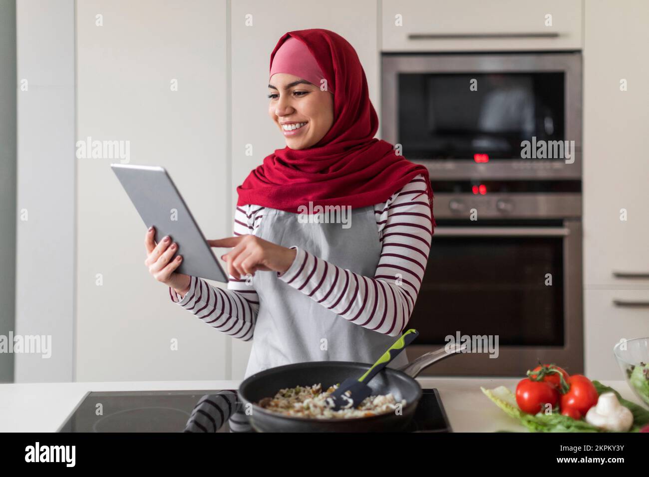 Middle eastern woman in hijab checking recipe on Internet Stock Photo ...