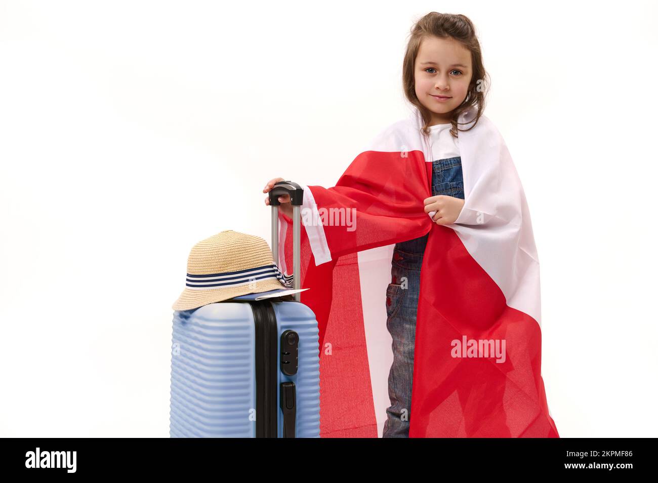 Cute little girl wrapping in Canada or Poland flag, smiles looking at ...