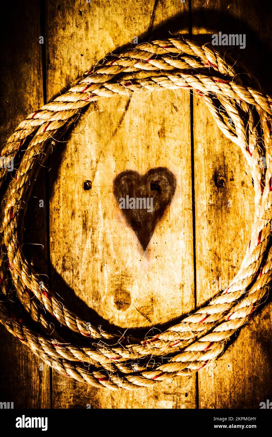 Symbol of maritime love etched in wooden surface surrounded by rope ...
