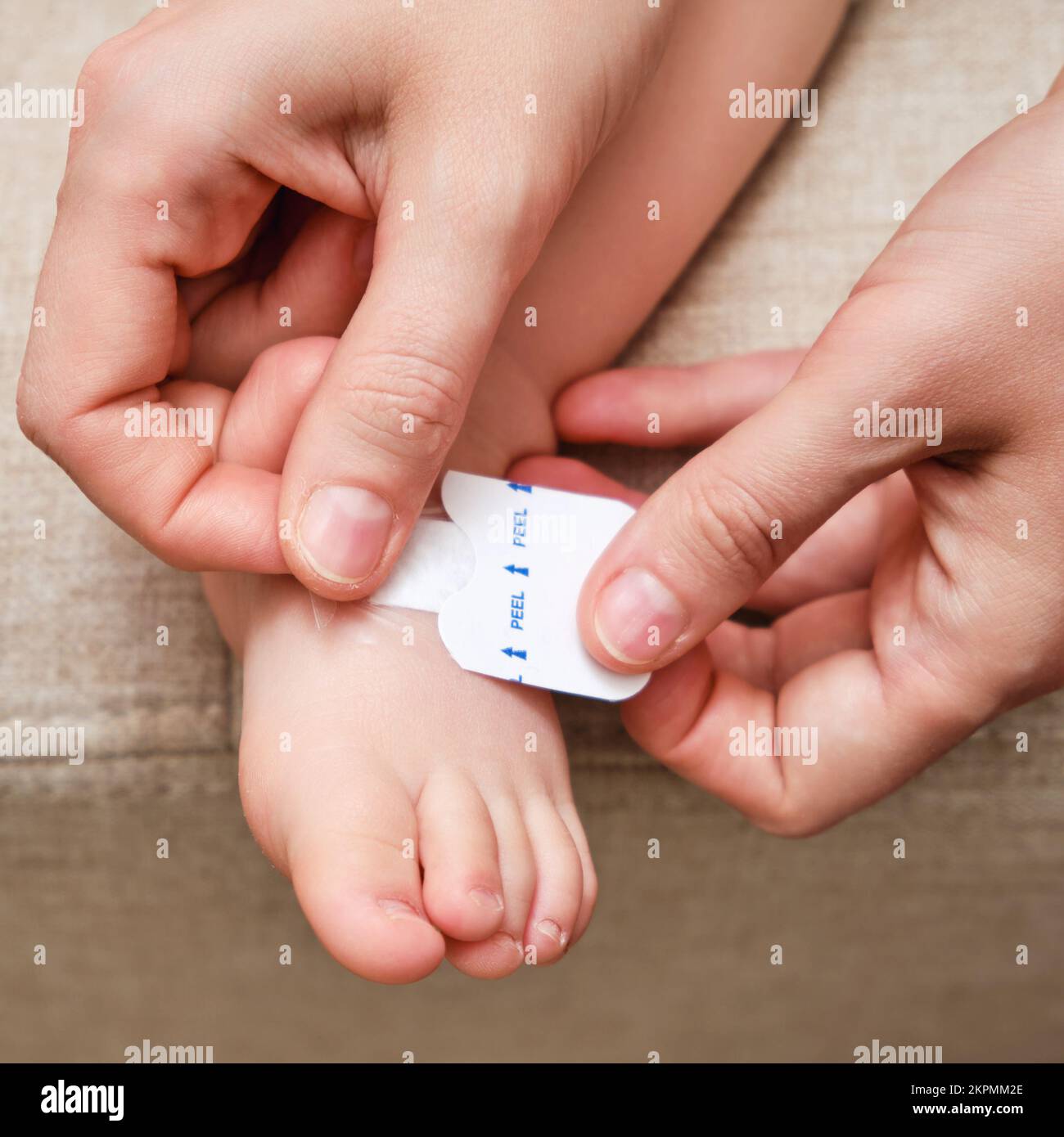 Mother woman sticks a medical adhesive plaster on the toddler baby leg ...