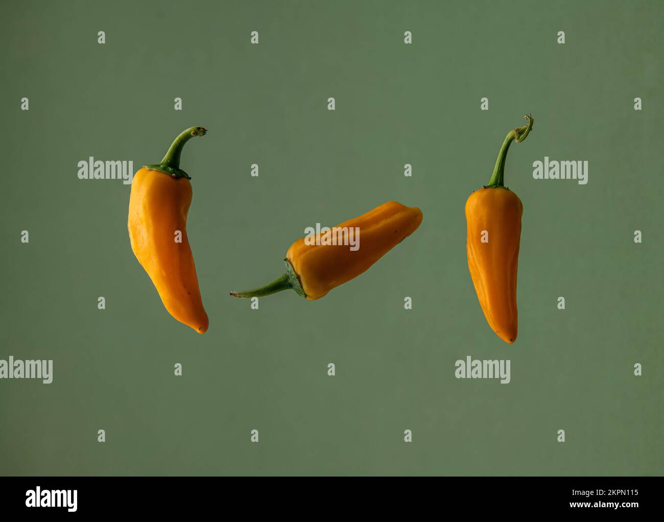 Three chillies floating and isolated on a green background Stock Photo ...