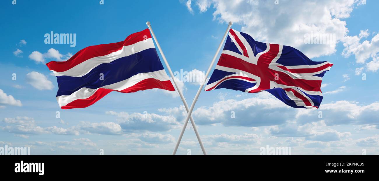 two crossed flags Great Britain and Thailand waving in wind at cloudy ...