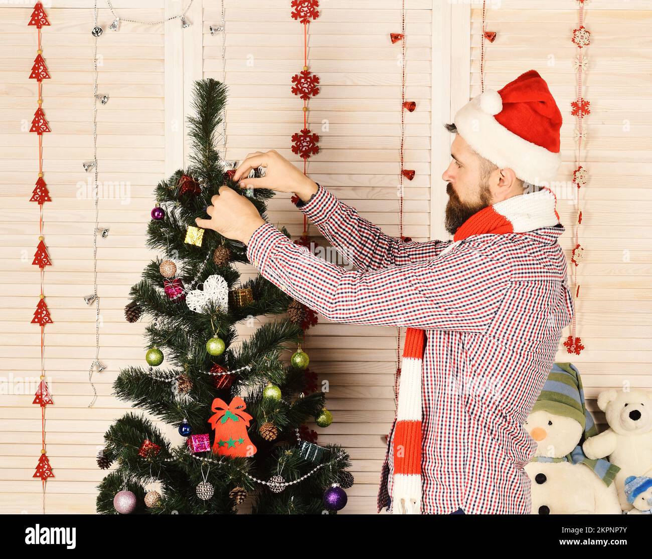 Man with beard in hat puts toy on fir tree Stock Photo - Alamy