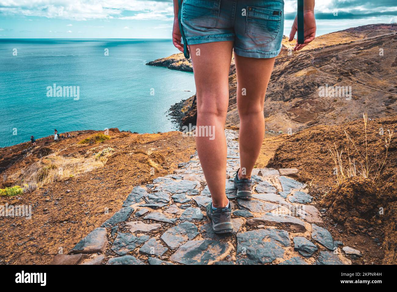 Description: Legs of sporty woman walking on a paved hiking trail with ...