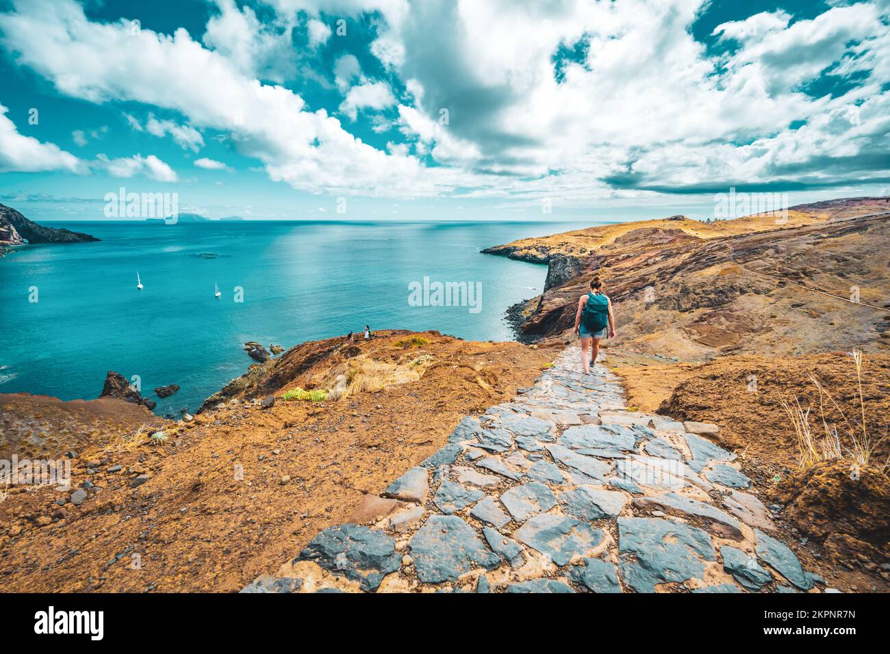 Description: Sporty woman walking on a paved hiking trail with ...