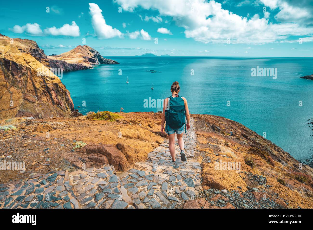 Description: Sporty woman walking on a paved hiking trail with ...