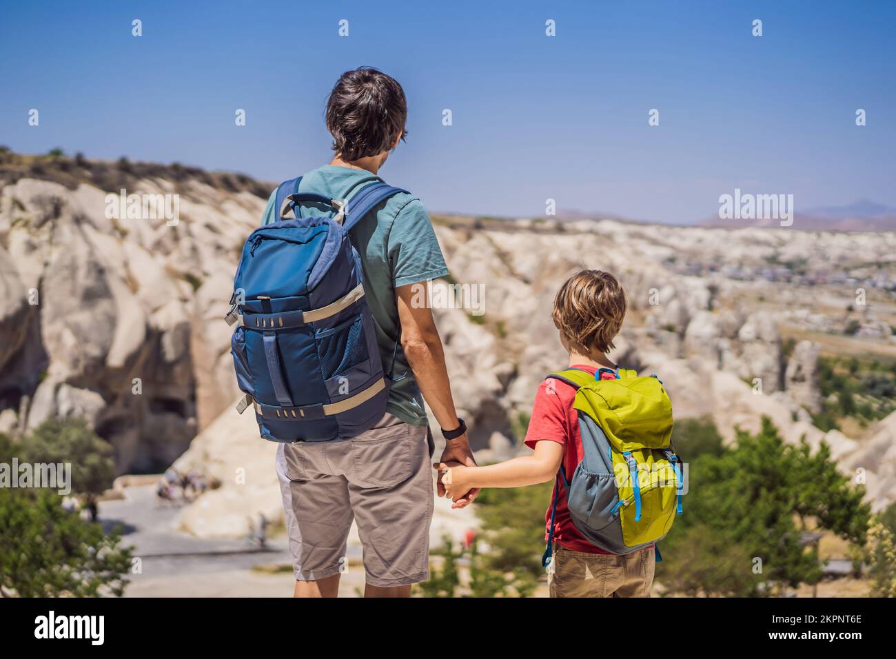 Father and son tourists exploring valley with rock formations and fairy ...