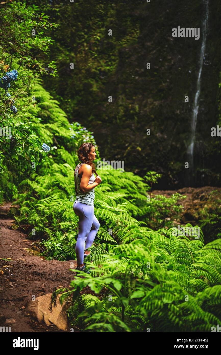 Description: Sporty woman marvels at nature at an impressive waterfall ...