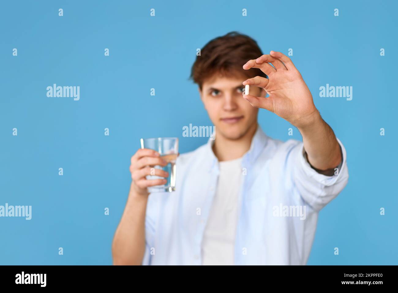 man holding pill and glass of water on blue background Stock Photo - Alamy