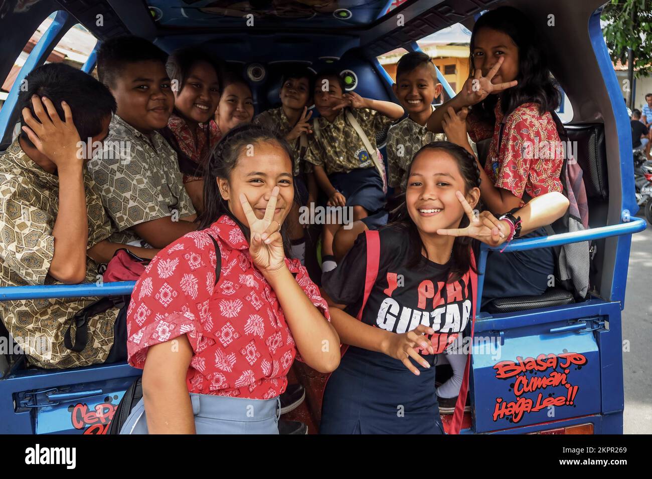 School children in uniform making the peace sign in angkot jeep ...