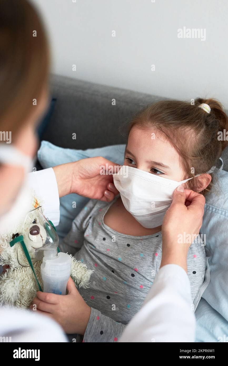 Doctor covering little patient's face with mask. Sick girl having ...