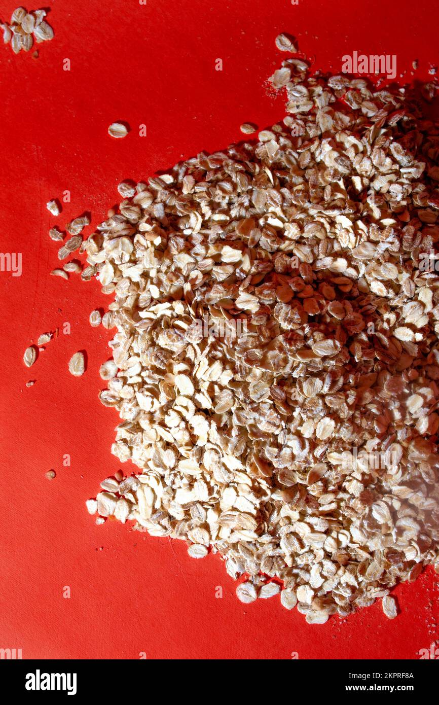 Pile of oat rye flakes on red color background Stock Photo - Alamy