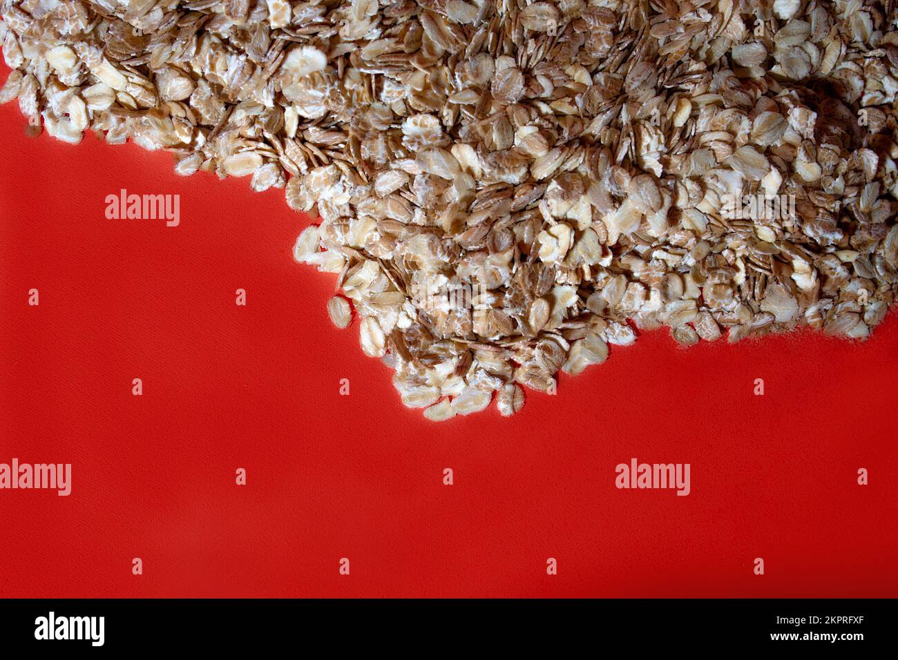 Pile of oat rye flakes on red color background Stock Photo - Alamy