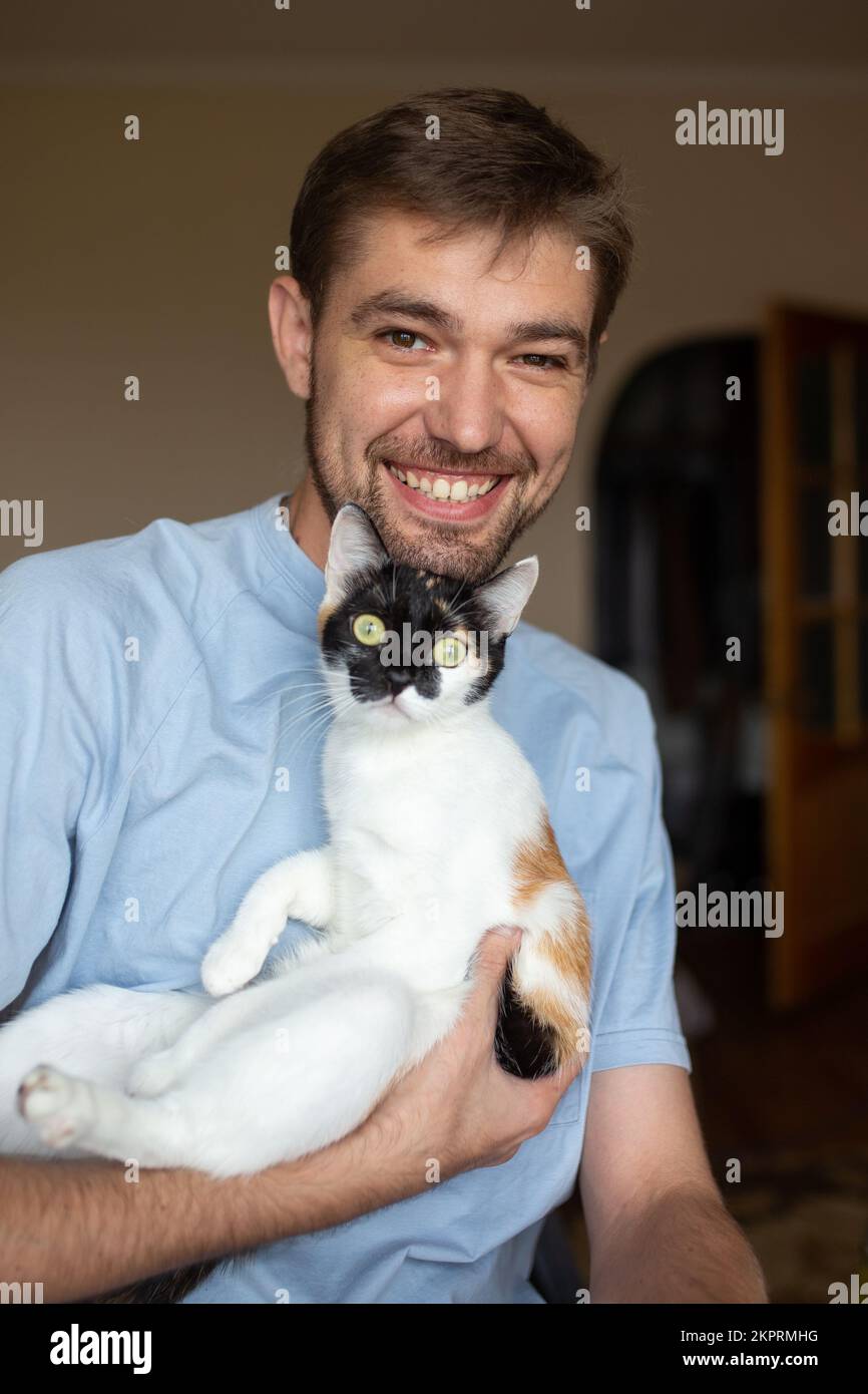 the guy smiles and holds the cat in his arms at home Stock Photo - Alamy