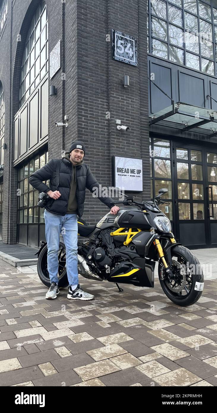 the guy with the camera is standing next to a new motorcycle Stock ...