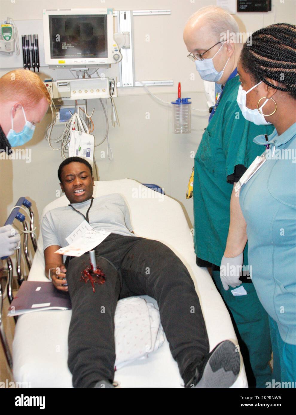 A volunteer simulates an injured patient preparing to receive care in ...