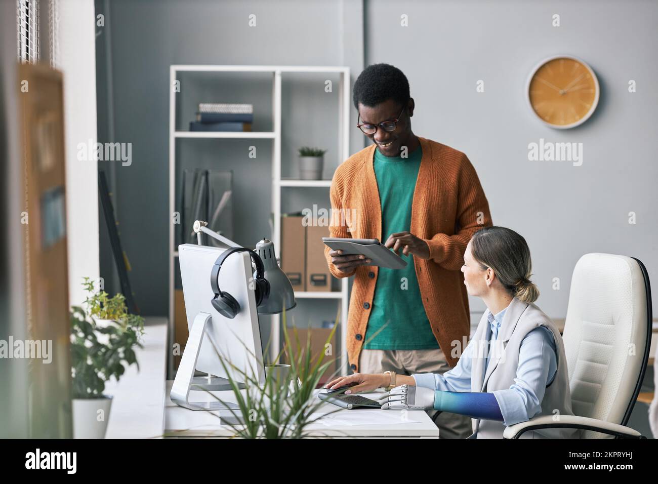 Smiling project manager discussing work with colleague with prosthetic ...