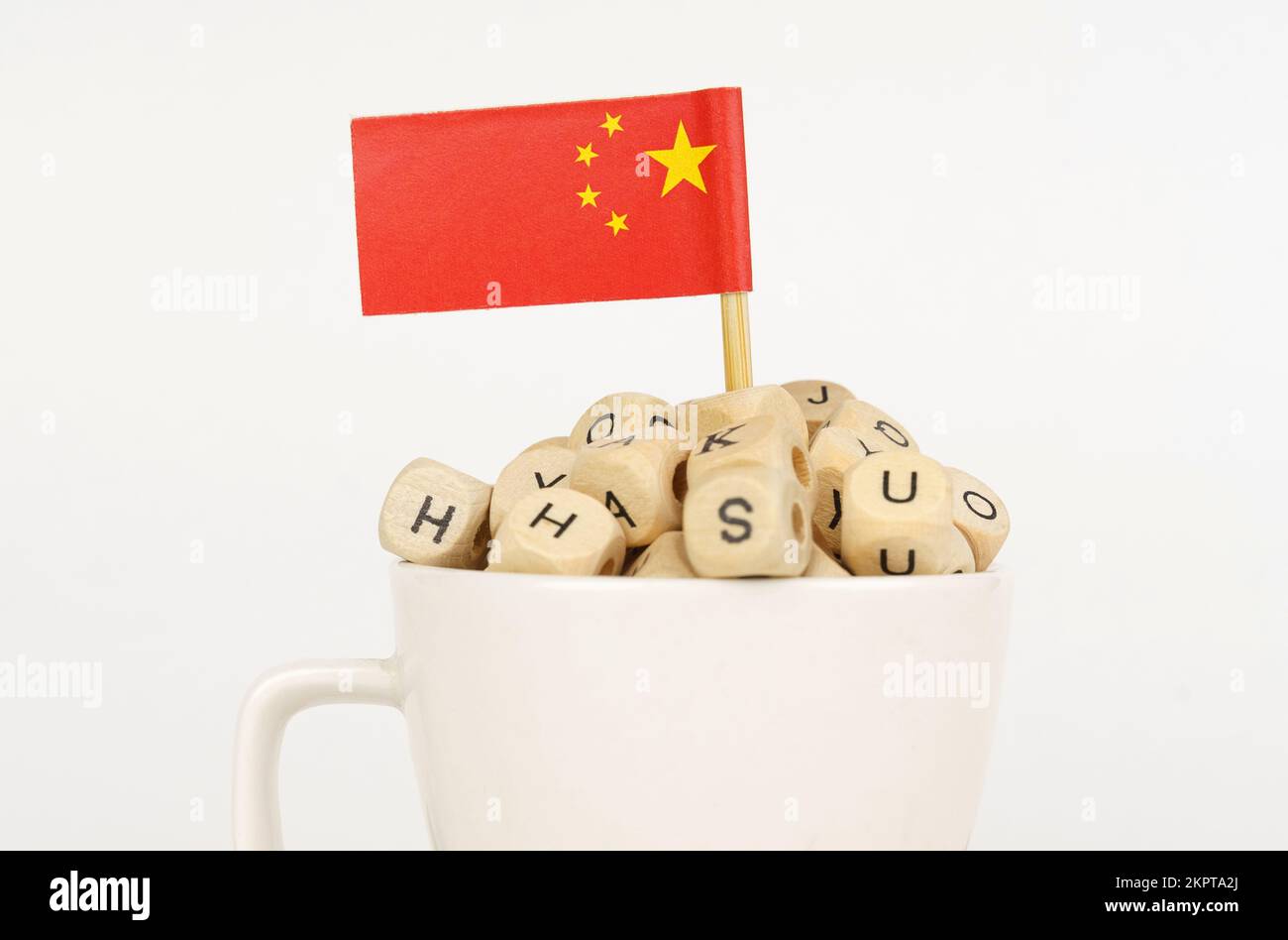 The flag of China sticks out of a cup with cubes on which letters are ...