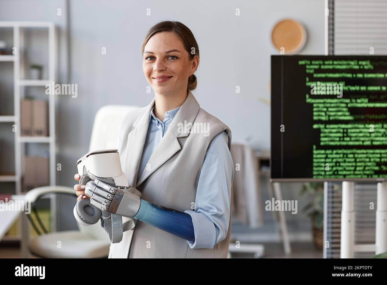 Portrait of smiling researcher with prosthetic arm holding VR glasses ...