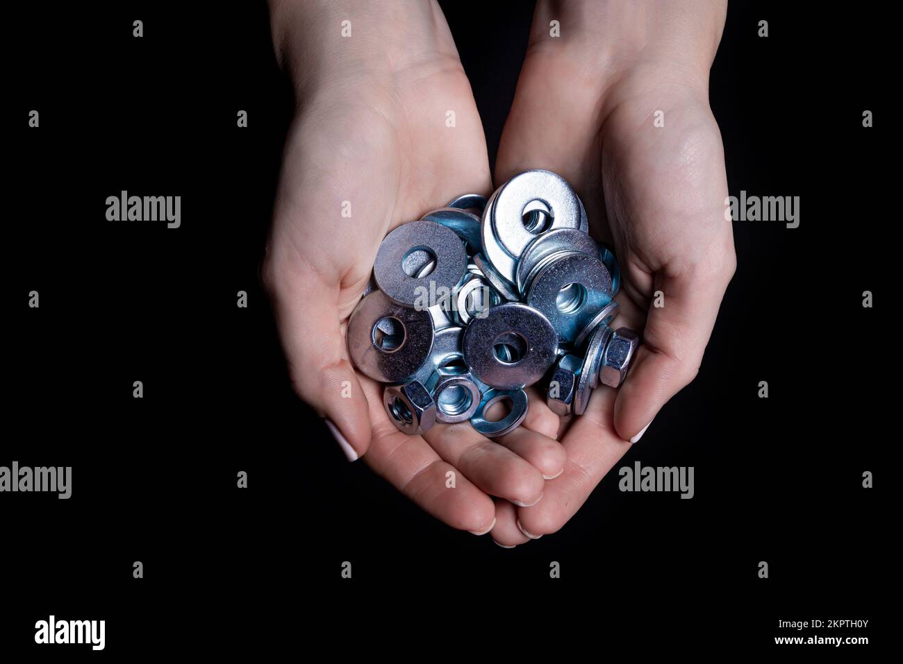 Woman's hands holding screws and dowels in palms. Isolated on black ...